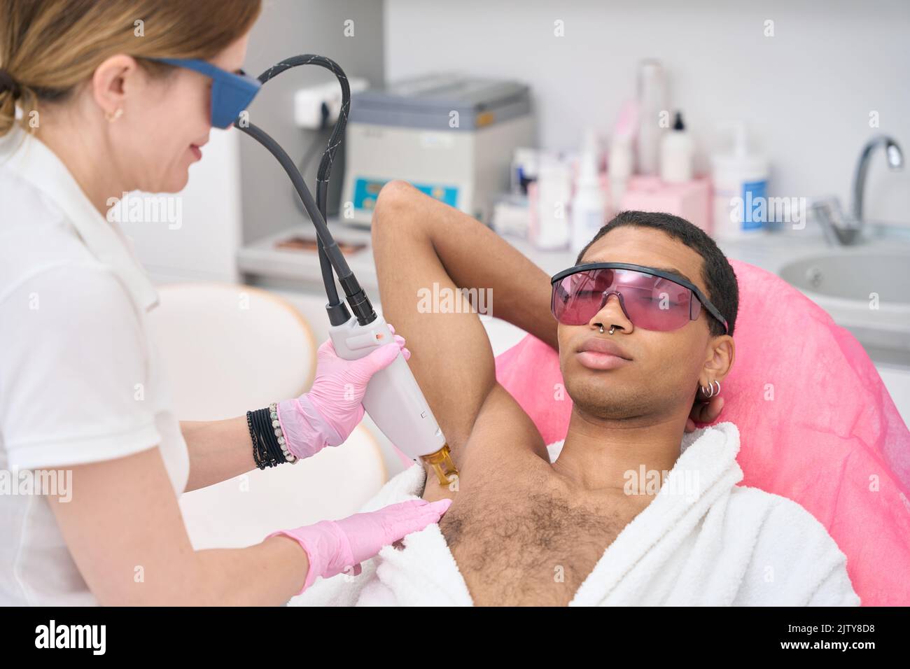 Experienced esthetician conducting underarm laser hair removal on ...