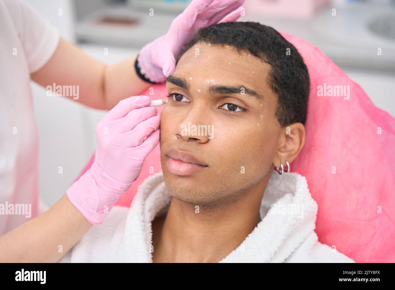 Beautician placing markings on patient face before cosmetic procedure ...