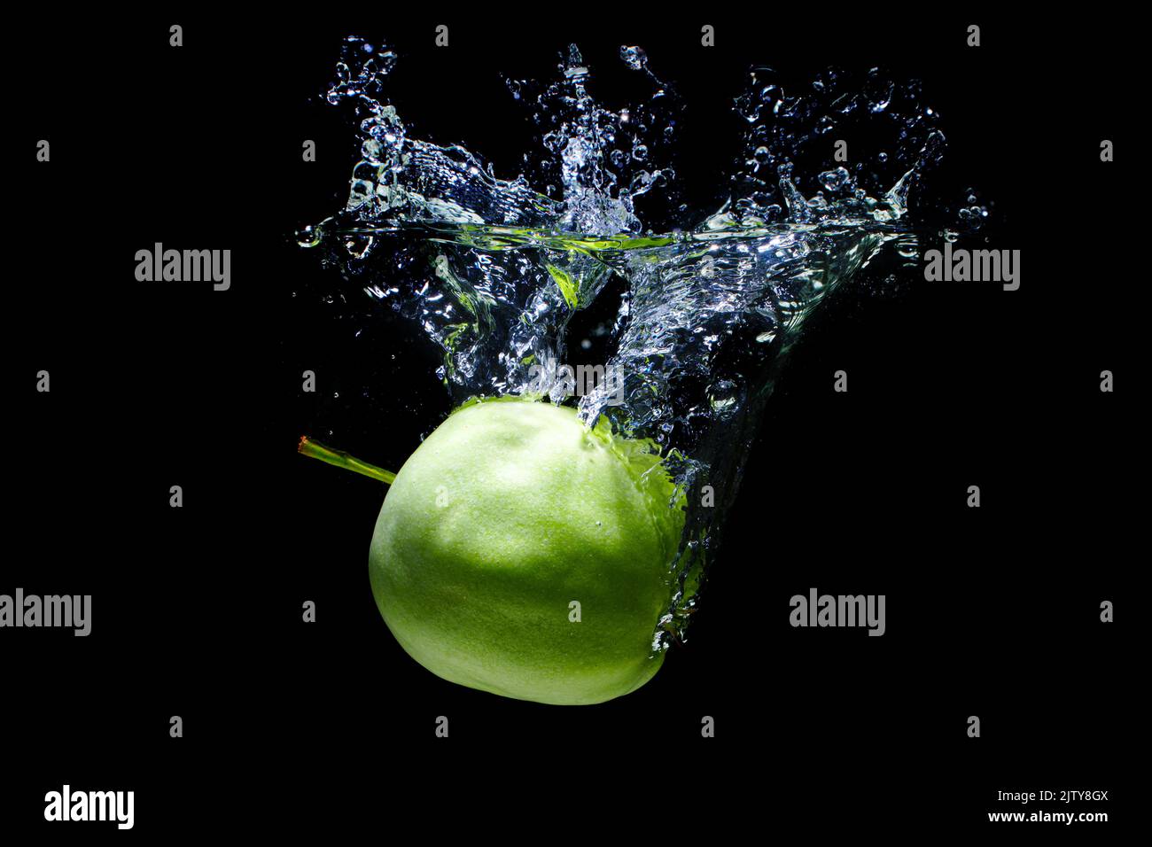 Fresh green apple going underwater with splashes and bubbles on black ...