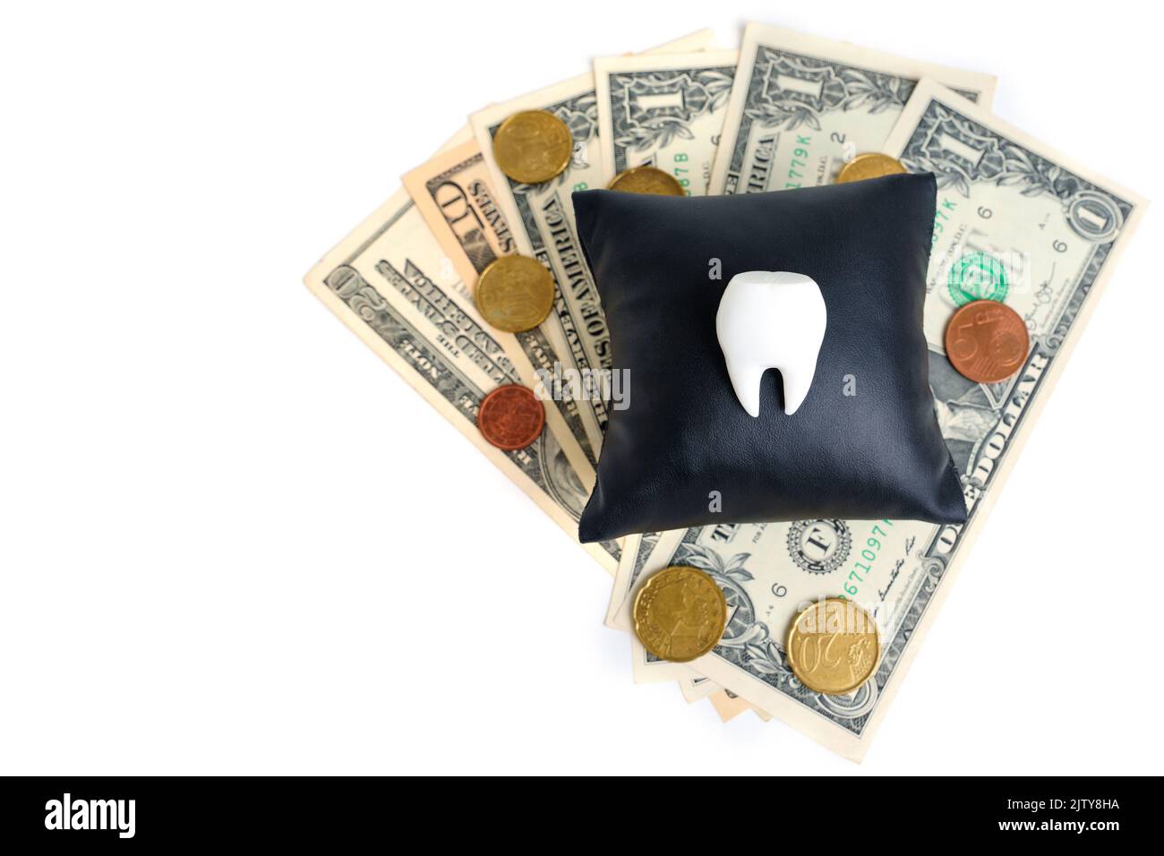 White tooth on a black leather pillow with some dollar bills and euro ...