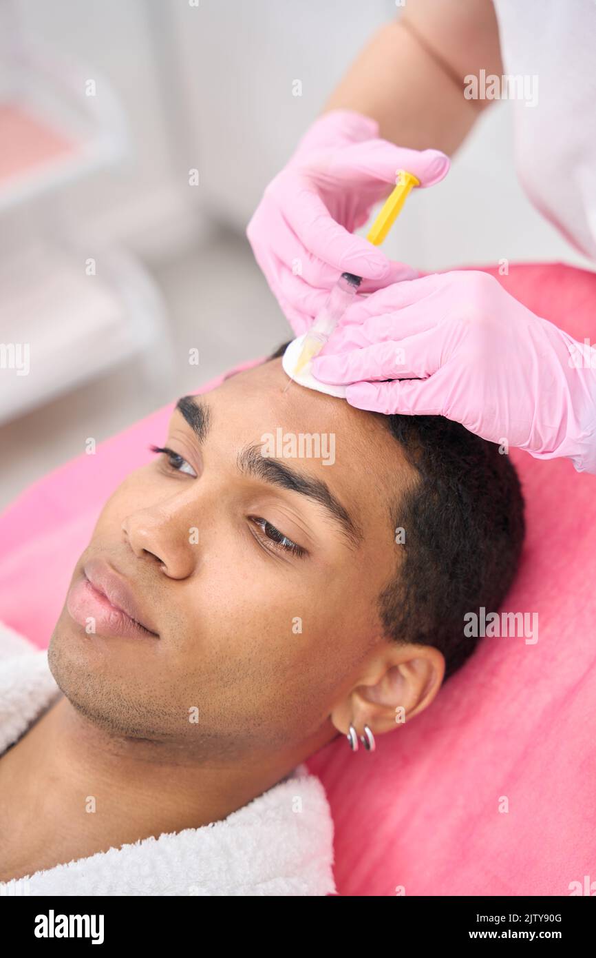 Aesthetic clinic client receiving dermal filler injection into forehead ...