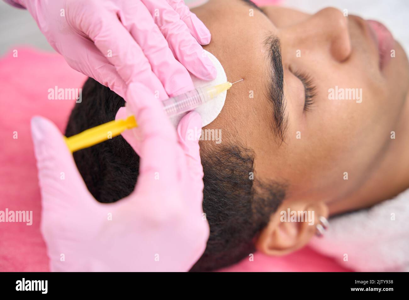 Beauty salon client getting dermal filler injection into forehead area ...