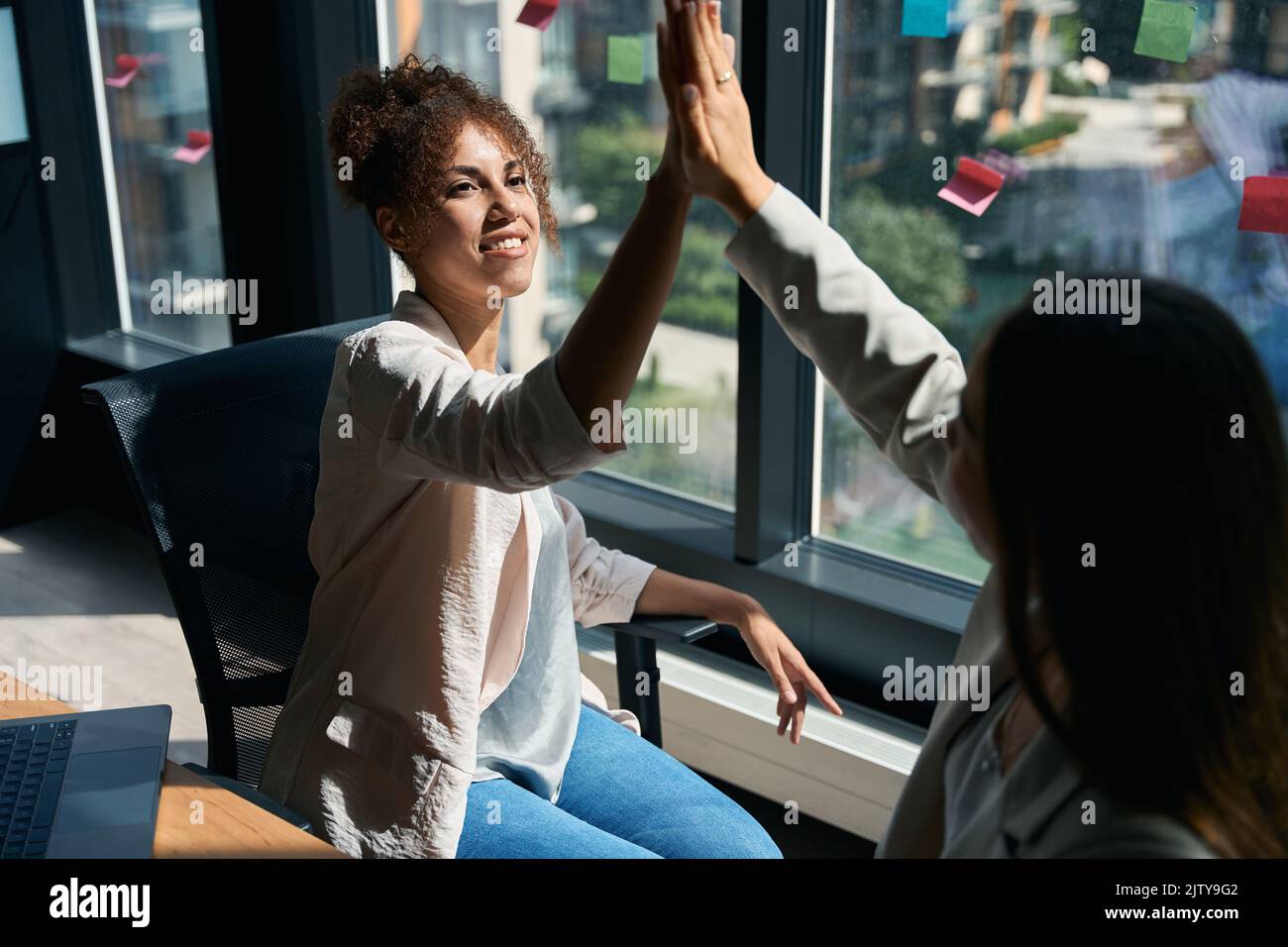 Pretty young women give each other high fives in coworking Stock Photo ...