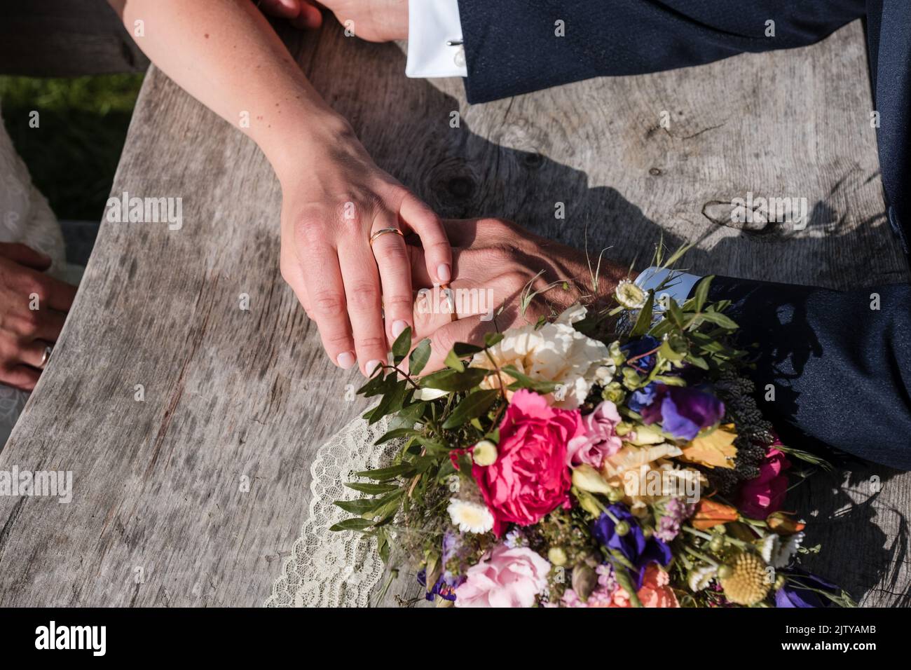 The bride's and groom's hands with wedding rings and the bouquet on ...
