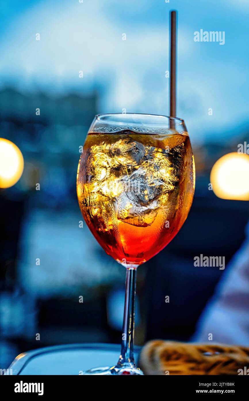 A cold alcoholic beverage aperol spritz with ice and straw against out ...