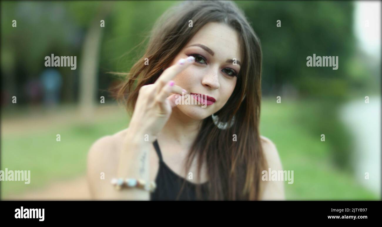 Pretty girl zipping mouth gesture keeping secret, looking to camera ...