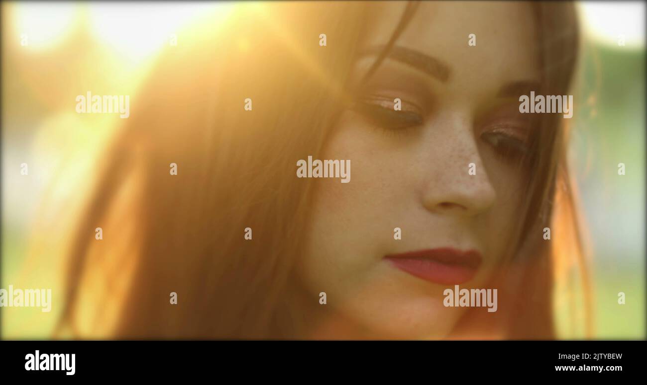 Pretty young woman posing to camera with lens-flare. Pensive girl in ...