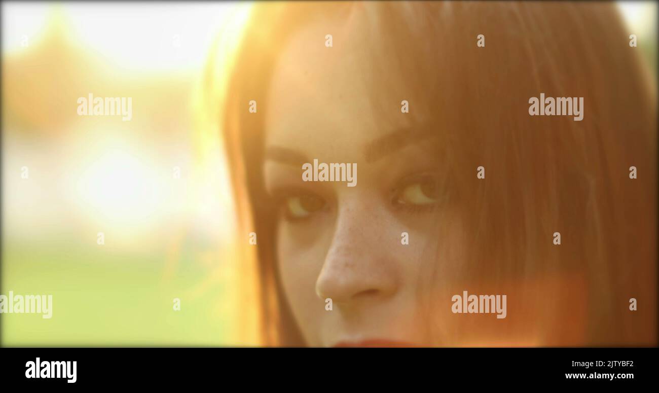 Pretty young woman posing to camera with lens-flare. Pensive girl in ...