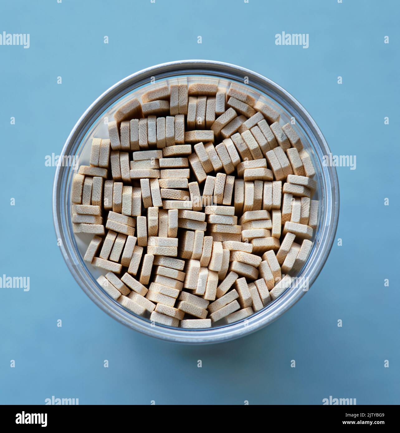 A collection of compacted wooden sticks in a round container, forming ...