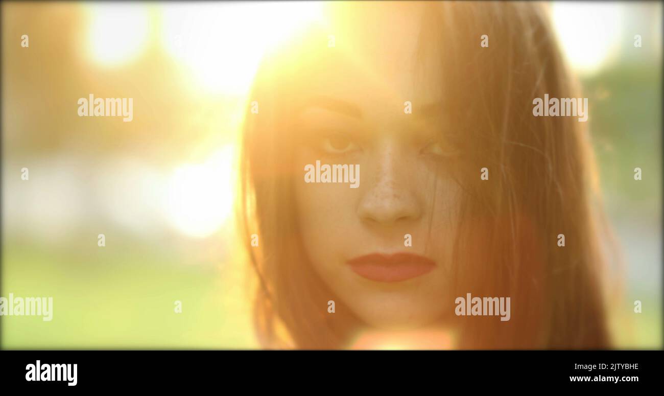 Pretty young woman posing to camera with lens-flare. Pensive girl in ...