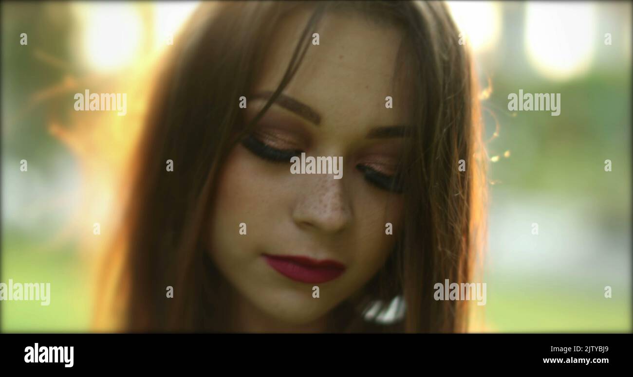 Pretty young woman posing to camera with lens-flare. Pensive girl in ...