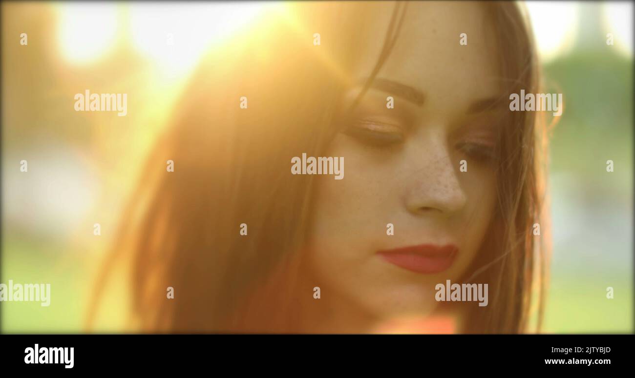 Pretty young woman posing to camera with lens-flare. Pensive girl in ...