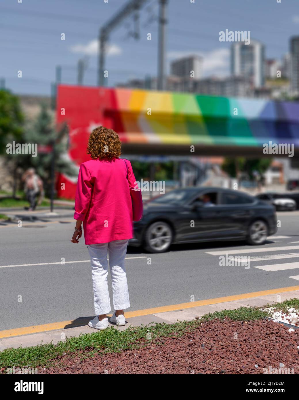 Rear view of pedestrian waiting in the wrong place to cross, not at a ...