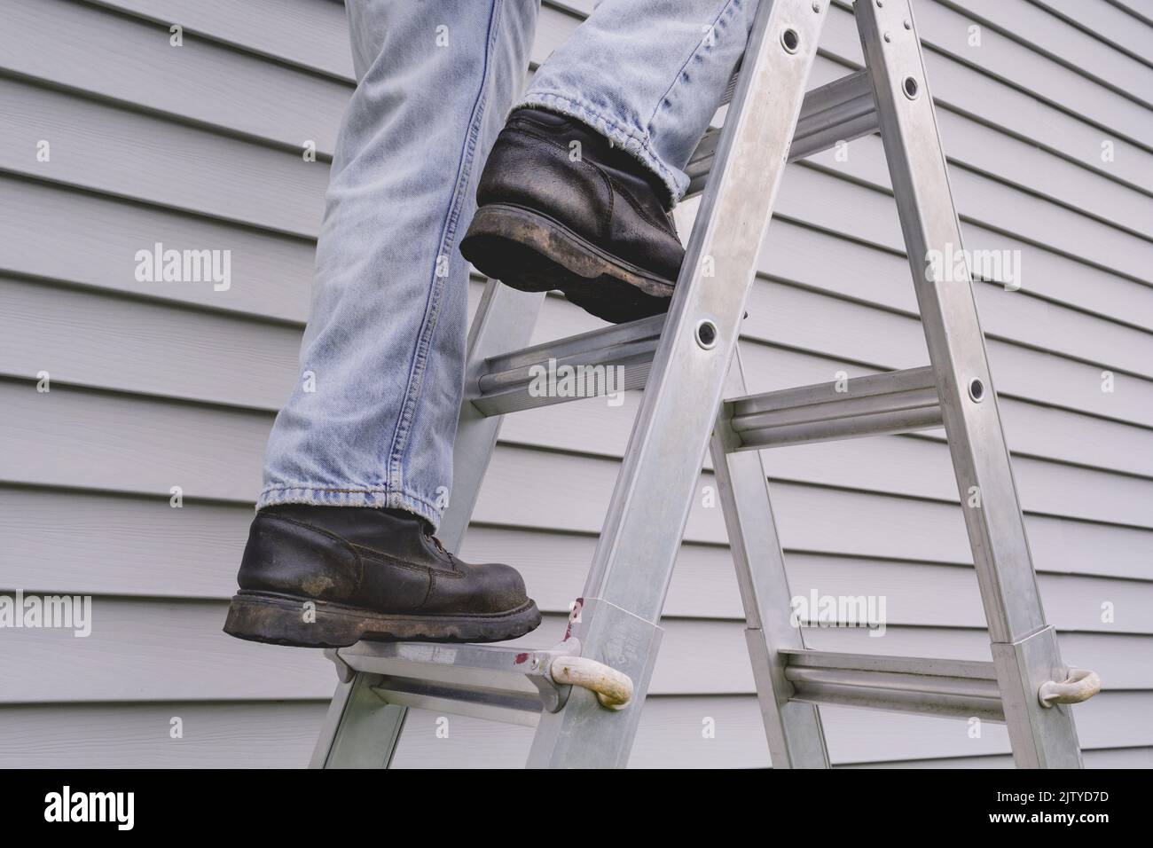 Male worker climbing stepladder in front of house siding Stock Photo ...