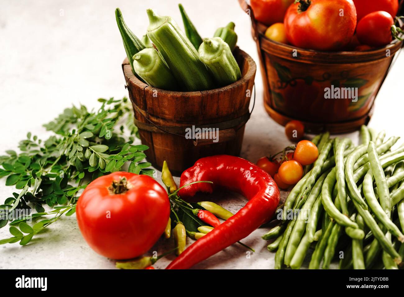 Still life of fresh homegrown vegetables cherry tomatoes green beans red pepper chillies okra ...