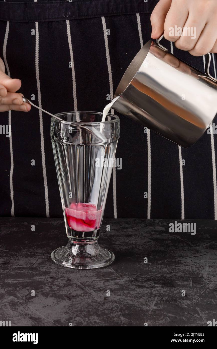 close-up of a barista making coffee with syrup and cream foam in a ...