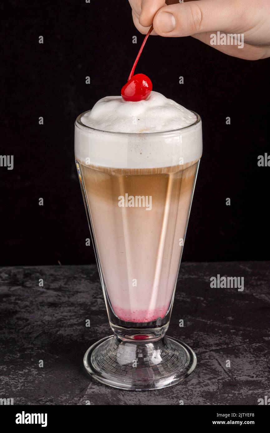 close-up of a barista making coffee with syrup and cream foam in a ...