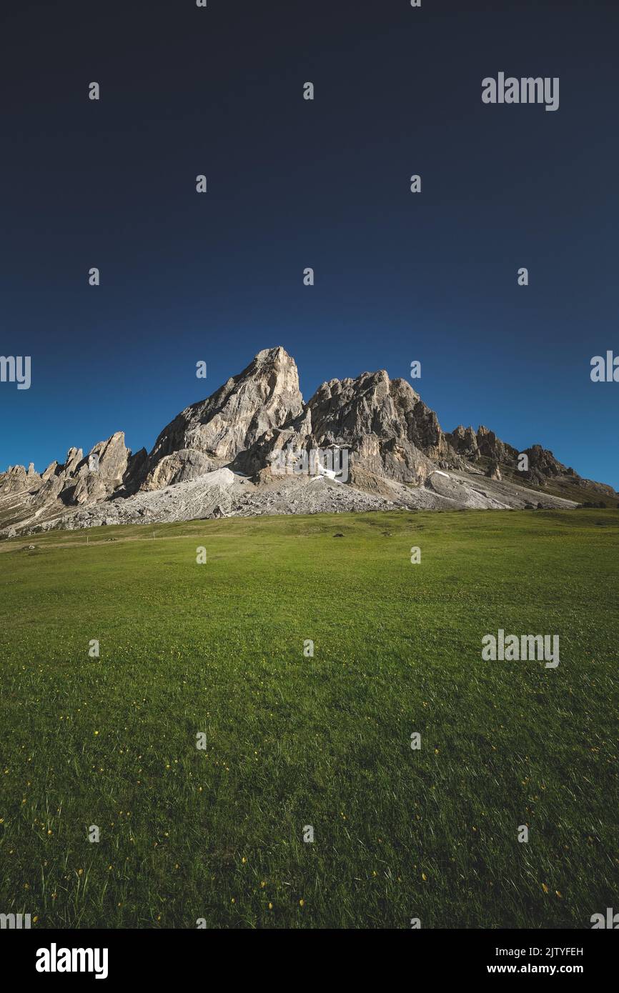 A rocky mountain landscape and greenfields against a clear blue sky ...