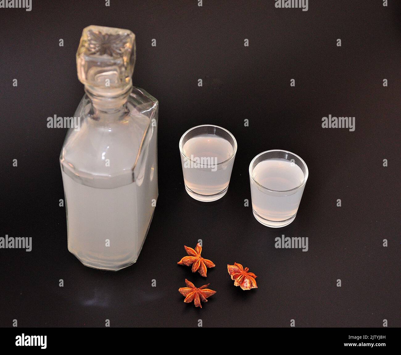 Anise liqueur, strong homemade alcohol and dried star anise fruits on a ...