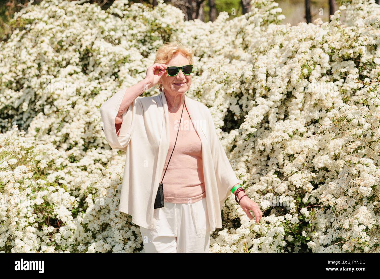 Elderly woman posing among bushes with white flowers Stock Photo - Alamy