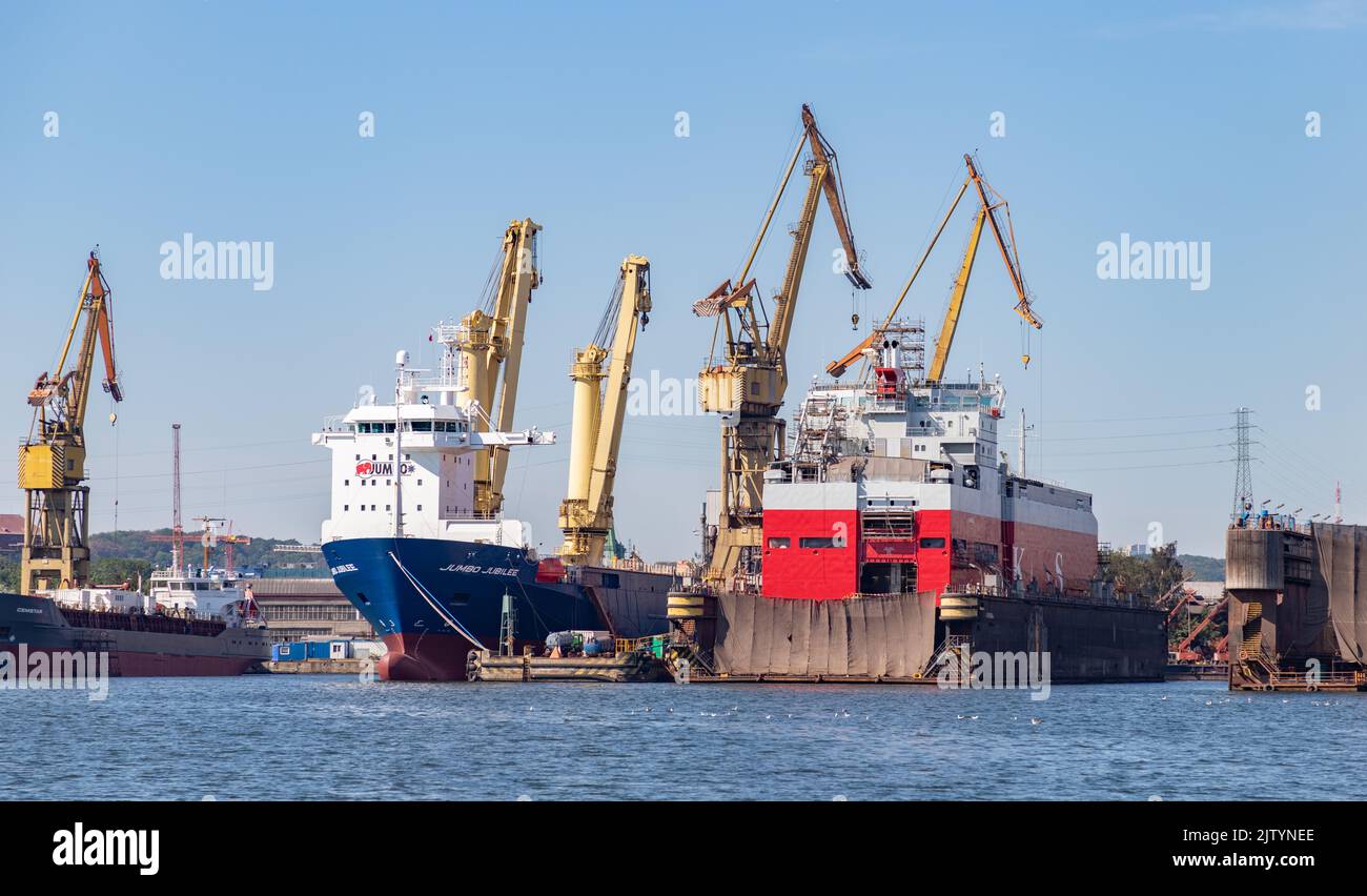 A picture of a vessel being repaired next to large cranes, as well as a ...