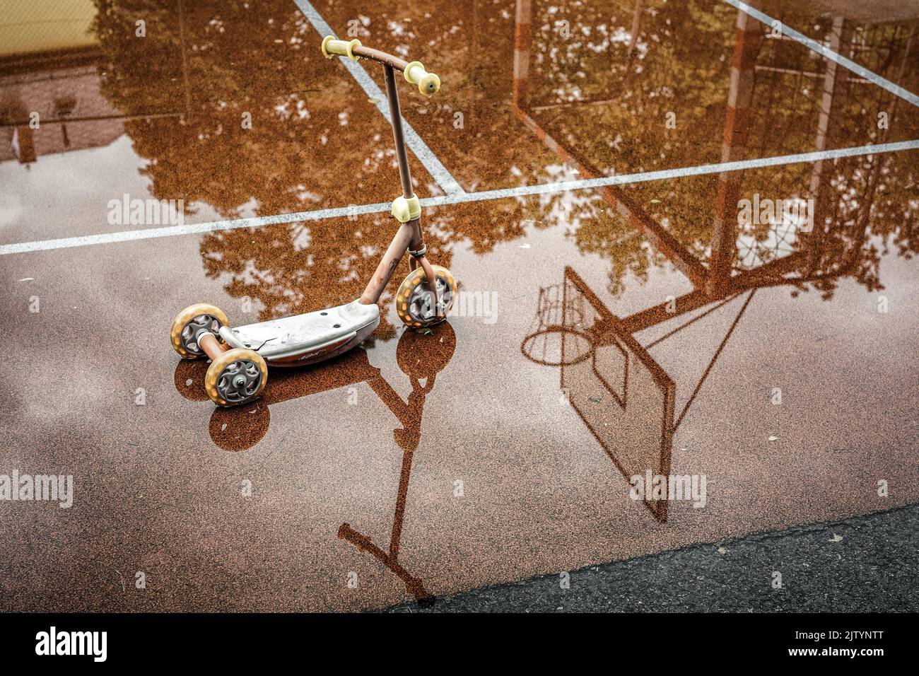 Reflection of children's scooter in the puddle at playground. Rainy ...