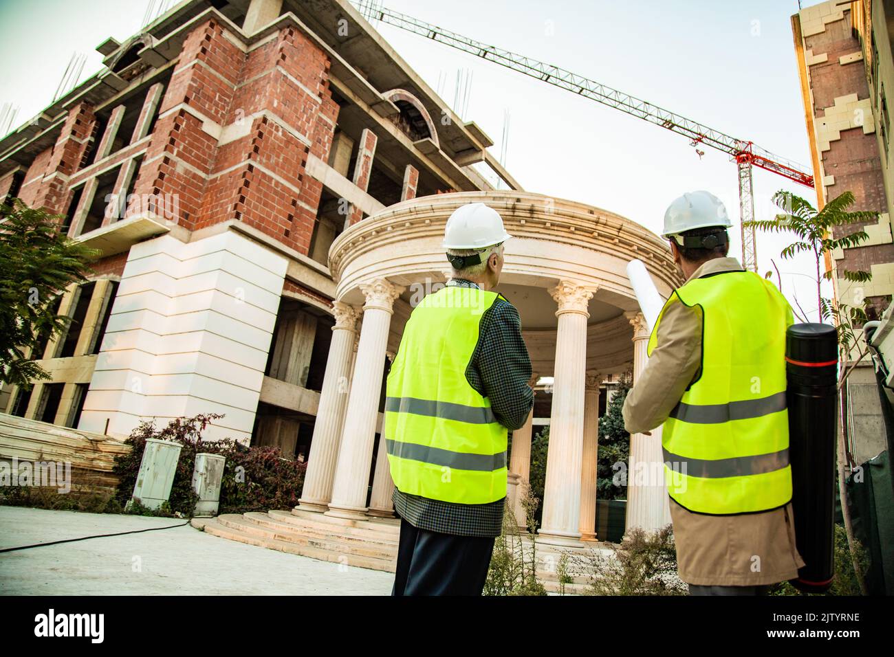 Two construction workers are looking at the construction area together ...