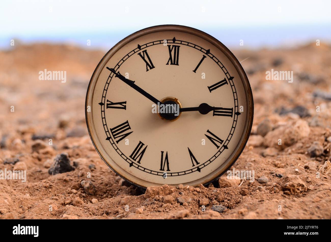 A classic analog clock in the sand on a rock desert Stock Photo - Alamy
