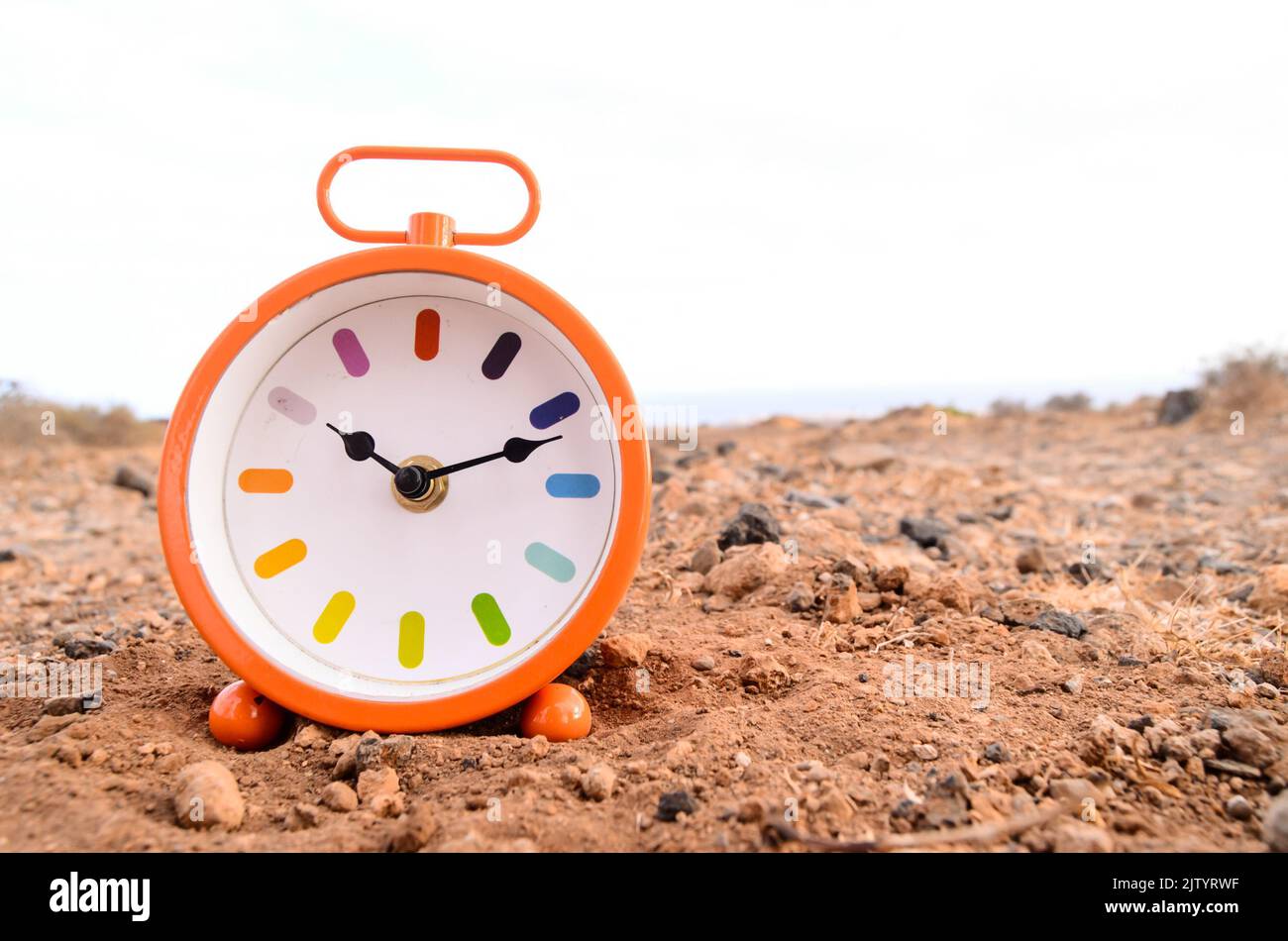 A classic analog clock in the sand on a rock desert Stock Photo - Alamy
