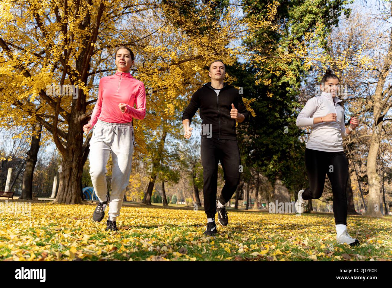 Three amazing and attractive fit friends are running and smiling ...