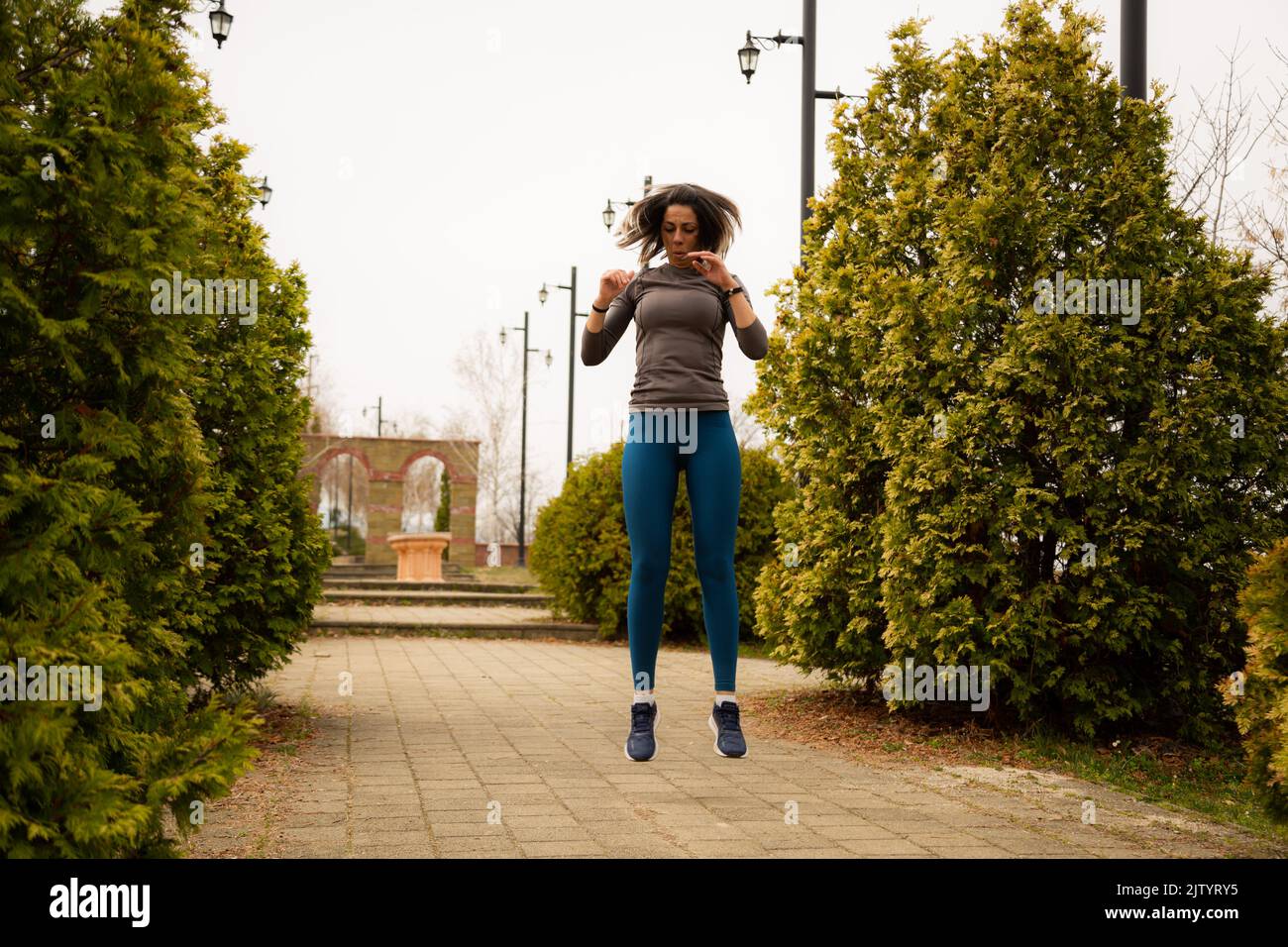 Middle aged woman jumping between the bushes Stock Photo - Alamy