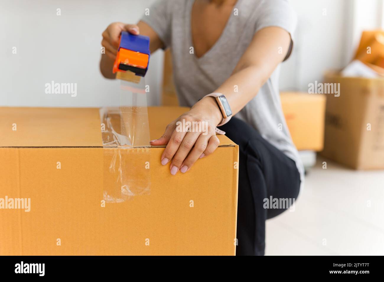 Asian business woman packing product sealing cardboard with duct tape ...