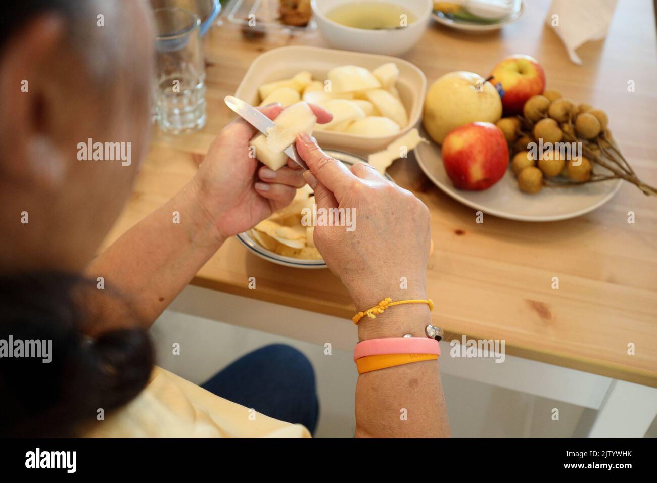 The senior Asian woman peeling some fruit in the dish Stock Photo - Alamy