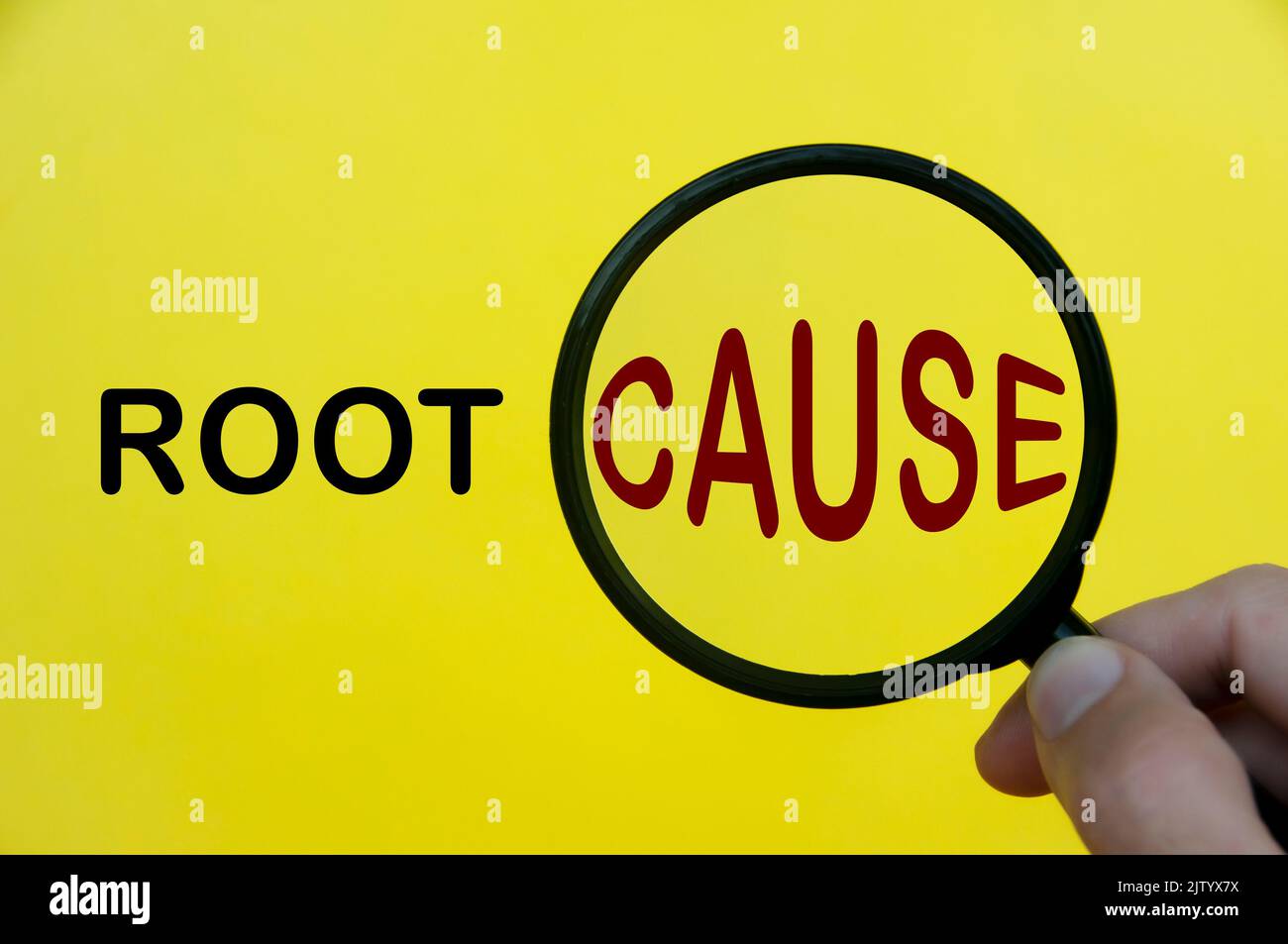 Close-up at root cause text through magnifying glass on yellow cover ...