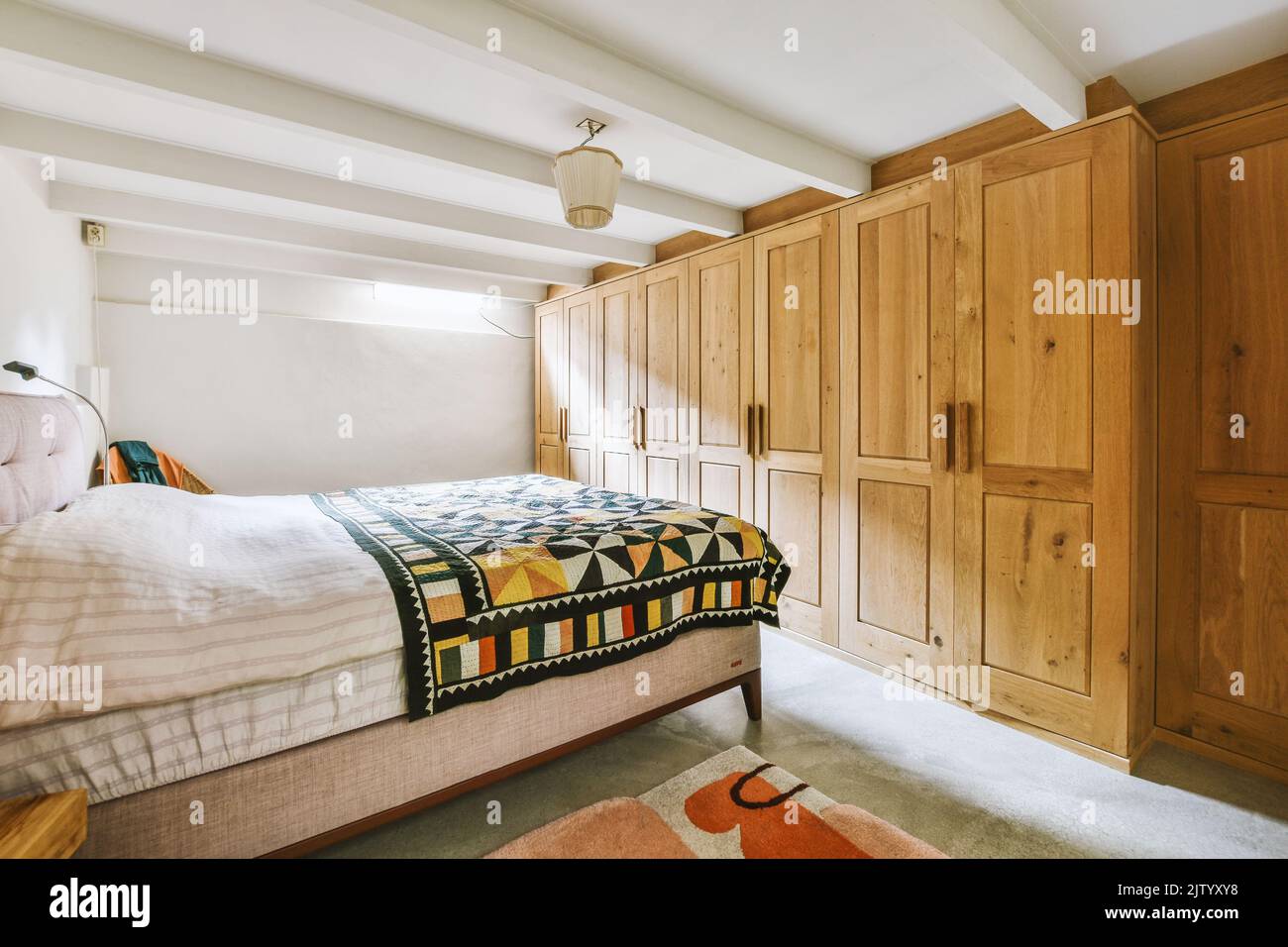 Home interior design of bedroom with bed and wooden wardrobe placed in ...