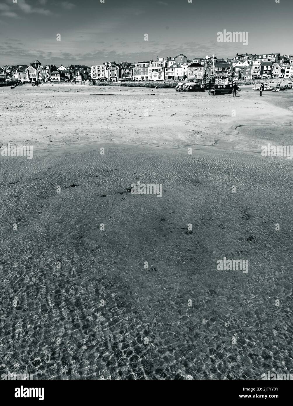 St Ives harbour at low tide with a shimmering rock pool. Black and ...