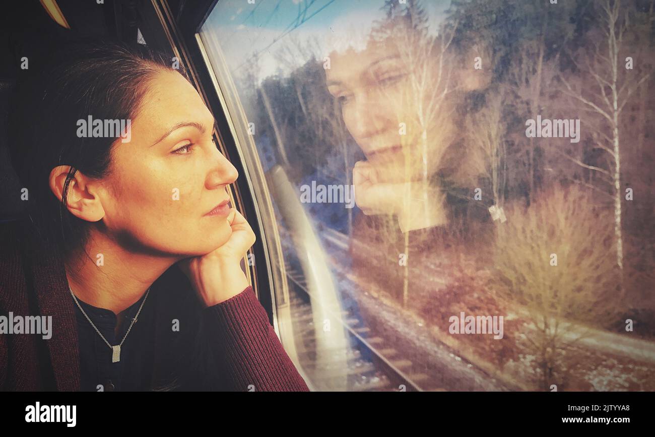 A closeup of a woman looking of the train window with nostalgic ...