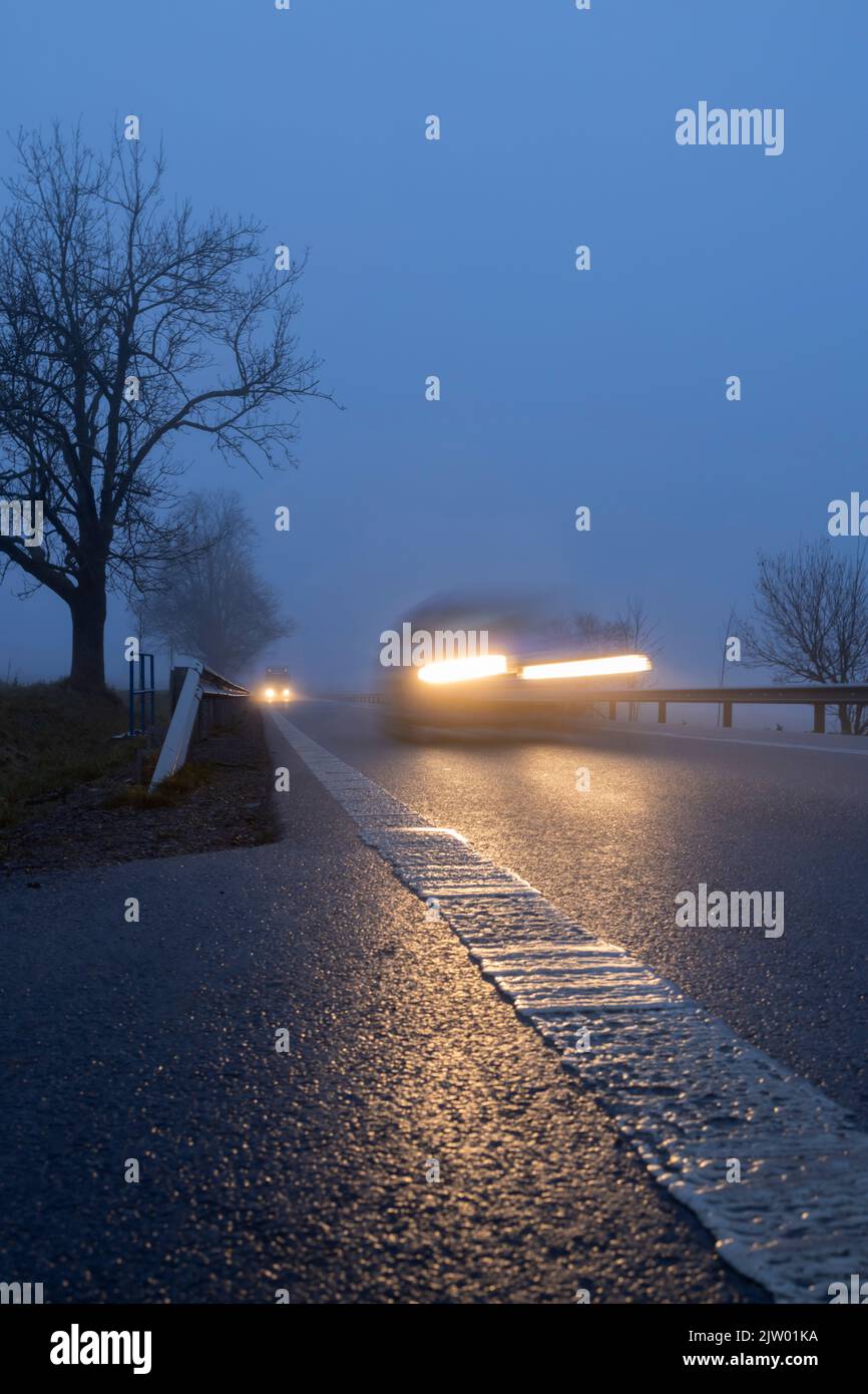 Lighted cars at dusk on main road Stock Photo - Alamy