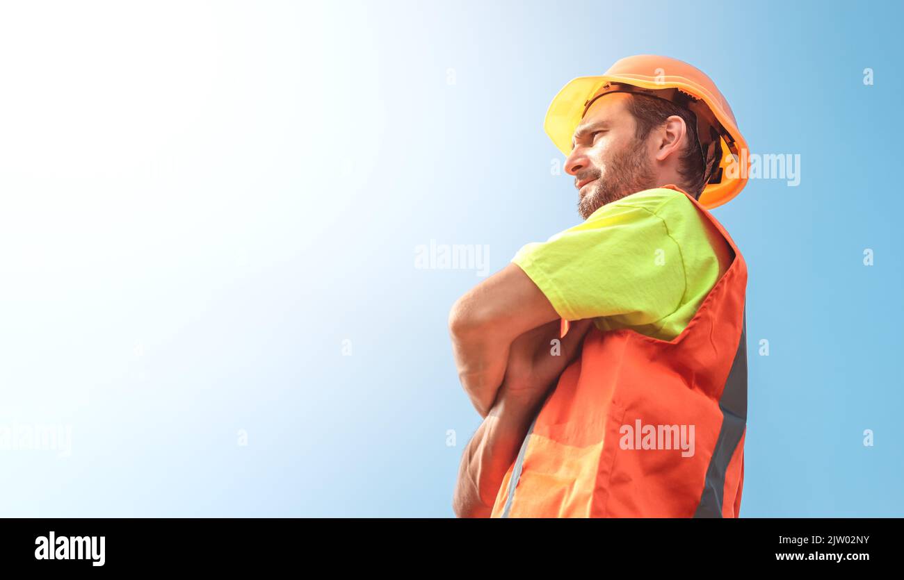 A portrait of a worker stands with confidence in an orange work suit ...