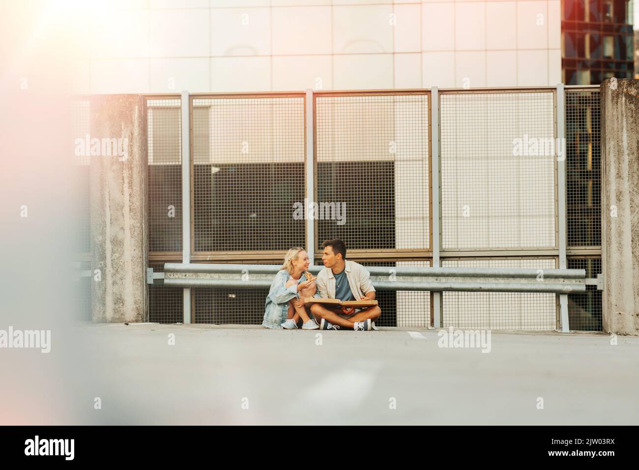 happy couple eating pizza on city roof top parking Stock Photo - Alamy