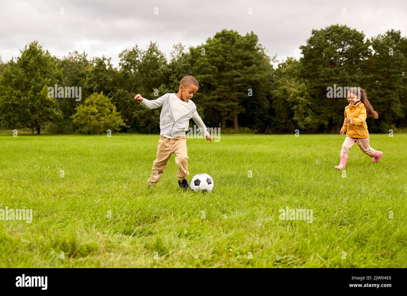 little children with ball playing soccer at park Stock Photo - Alamy