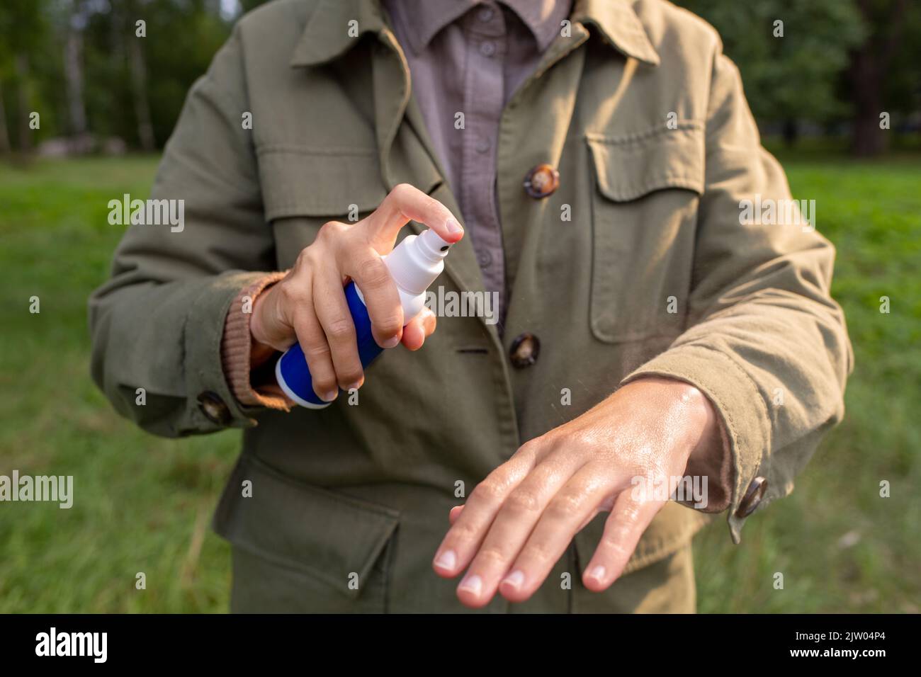 woman spraying insect repellent to hand at park Stock Photo - Alamy