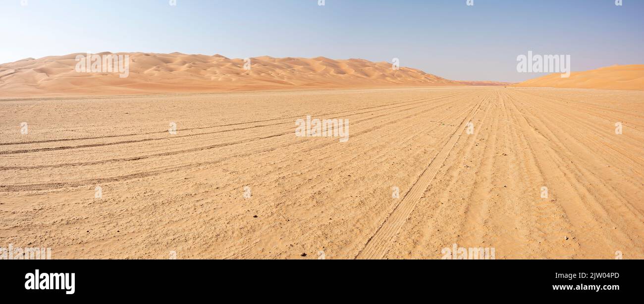 Panoramic view of a sand track in the desert with blue sky and copy ...