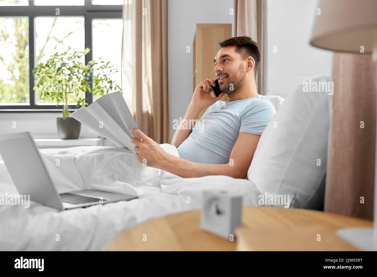 man with folder calling on phone in bed at home Stock Photo - Alamy