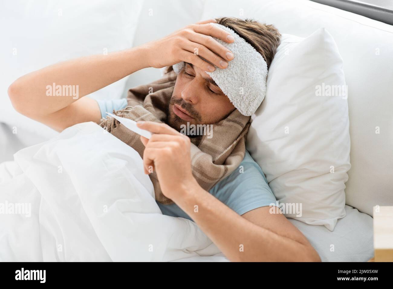 sick man measuring temperature by thermometer Stock Photo - Alamy