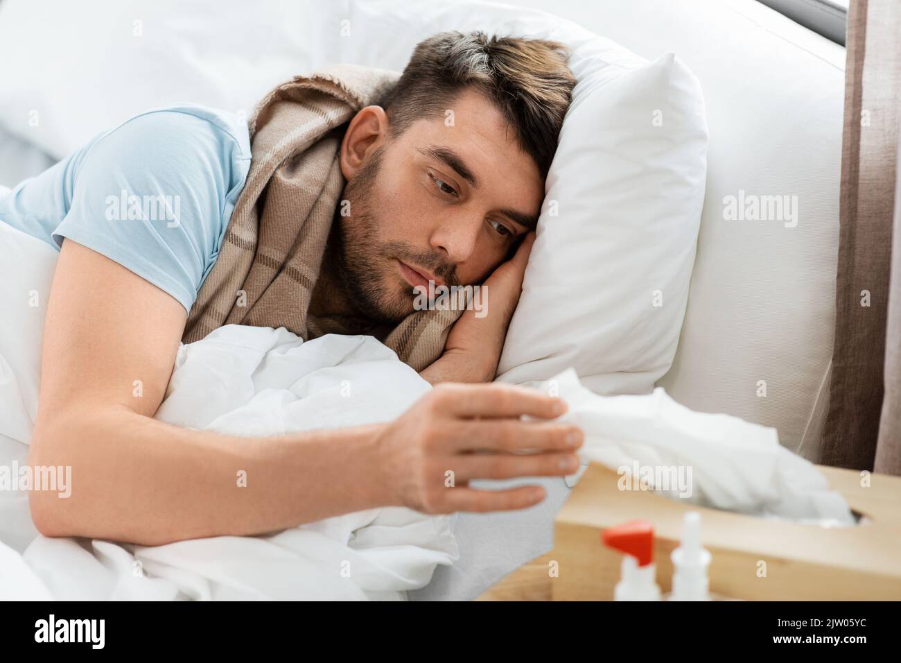 sick man lying in bed at home and taking tissue Stock Photo - Alamy