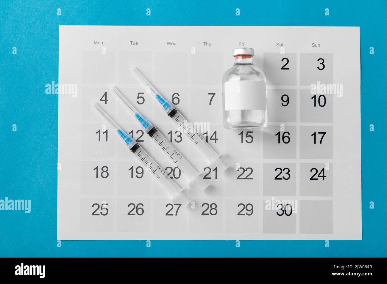 disposable syringe and calendar on blue background Stock Photo - Alamy