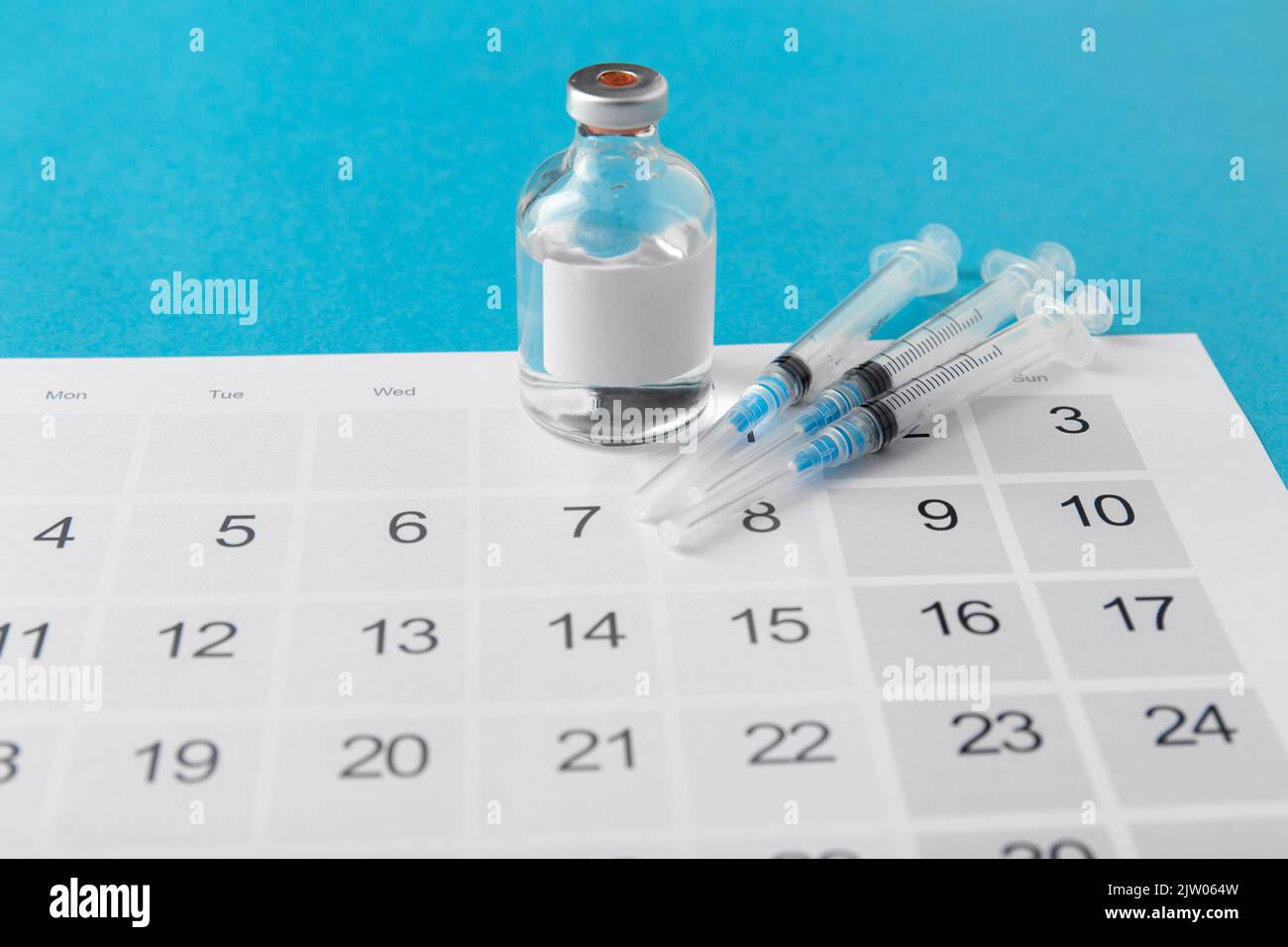disposable syringe and calendar on blue background Stock Photo - Alamy