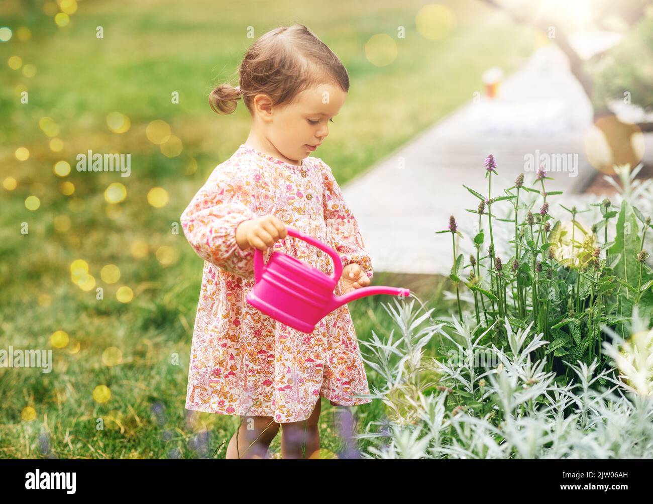 happy baby girl with watering can in summer garden Stock Photo - Alamy