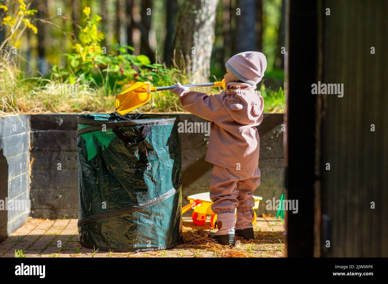 happy little baby girl helping clean up backyard Stock Photo - Alamy